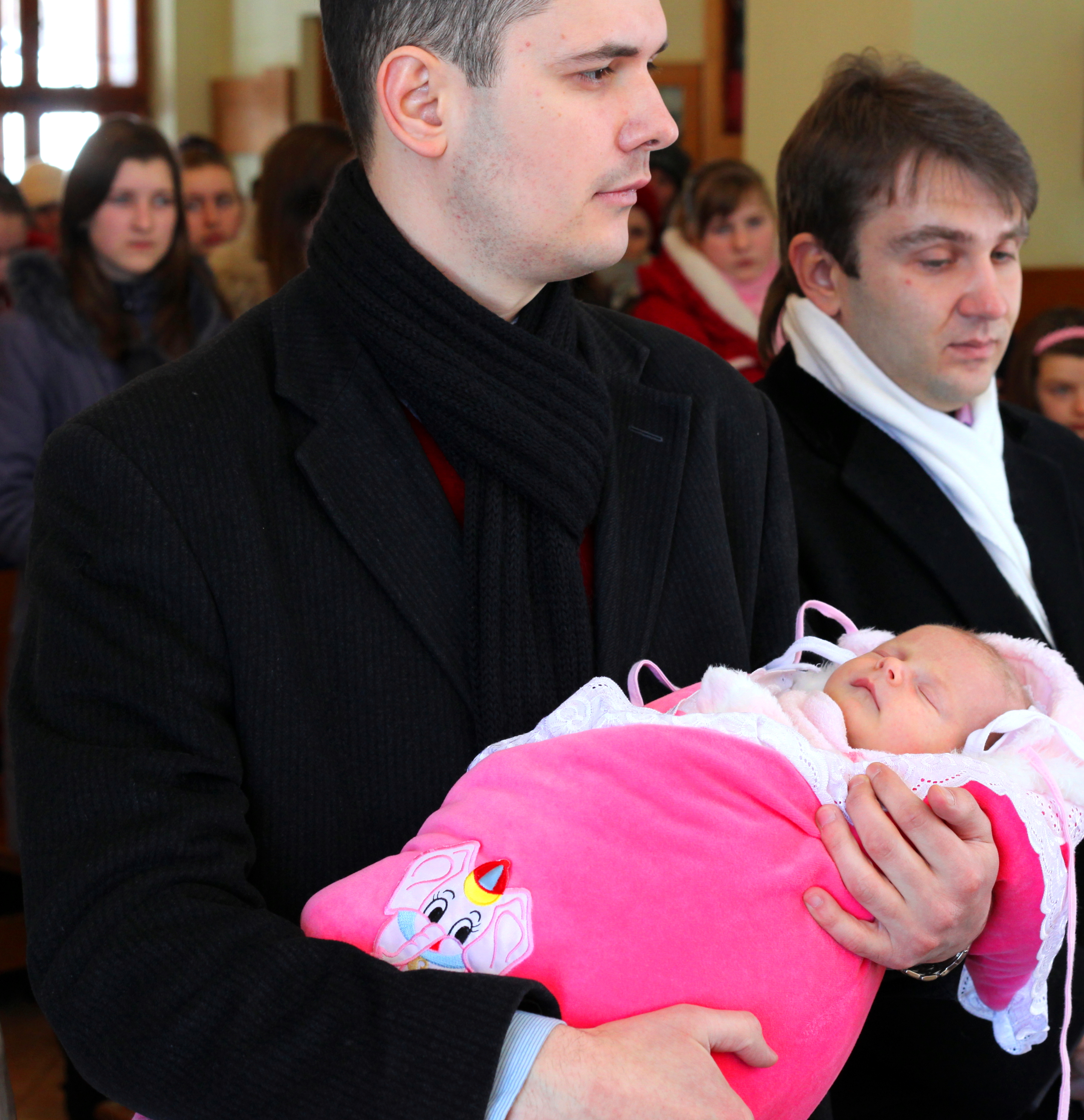 Photo of father holding his baby daughter during her christening in a ...